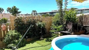 Um quintal com piscina, cerca de madeira e diversas plantas.
