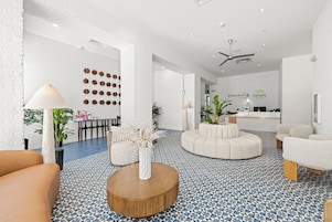 Um hall de hotel moderno com piso estampado em padrão geométrico, um balcão de recepção e áreas de estar confortáveis.