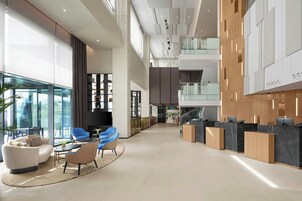 Um hall amplo com balcão de recepção, área de estar e escadaria para os andares superiores.
