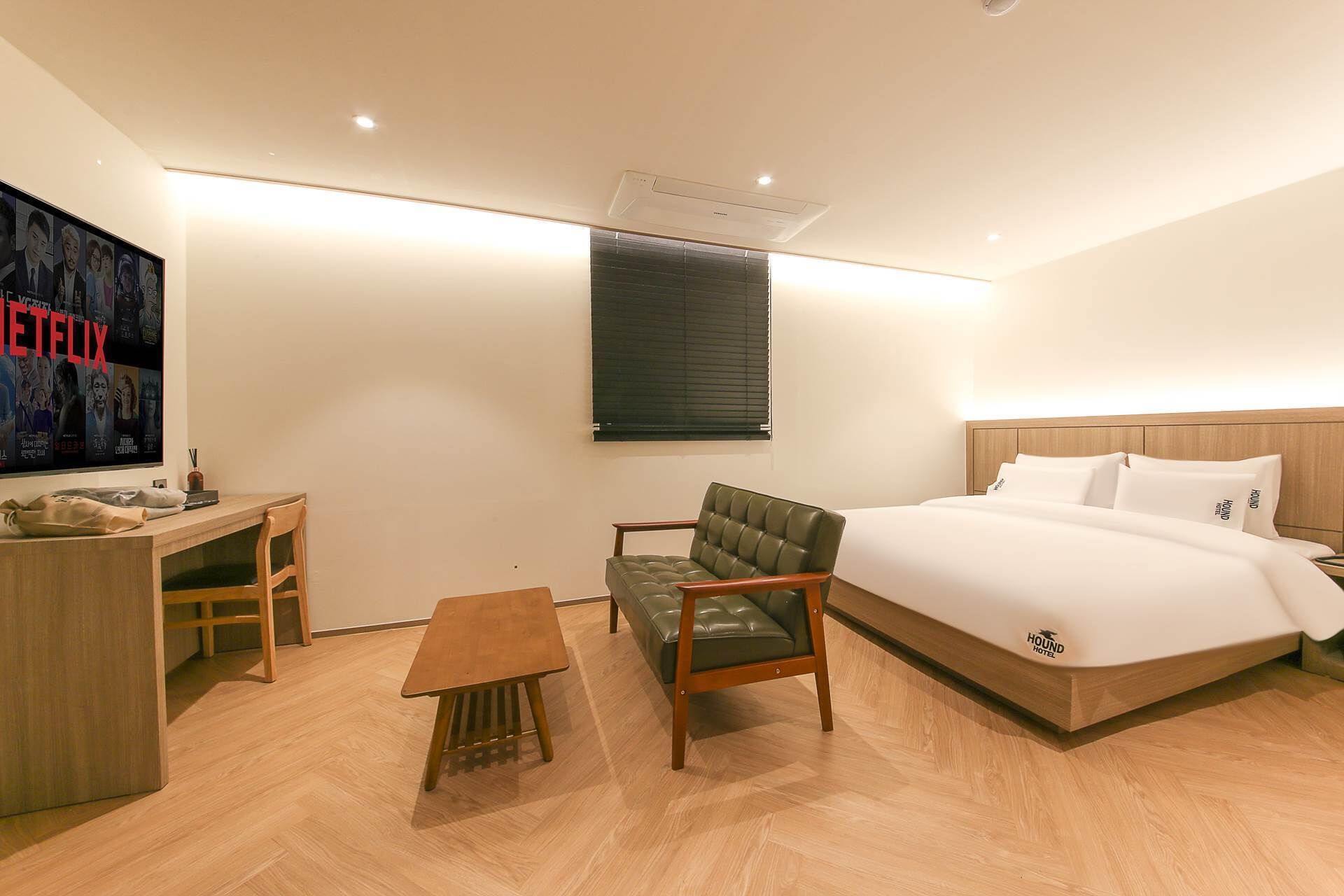 Quarto de hotel moderno com cama, escrivaninha, cadeira e televisão.