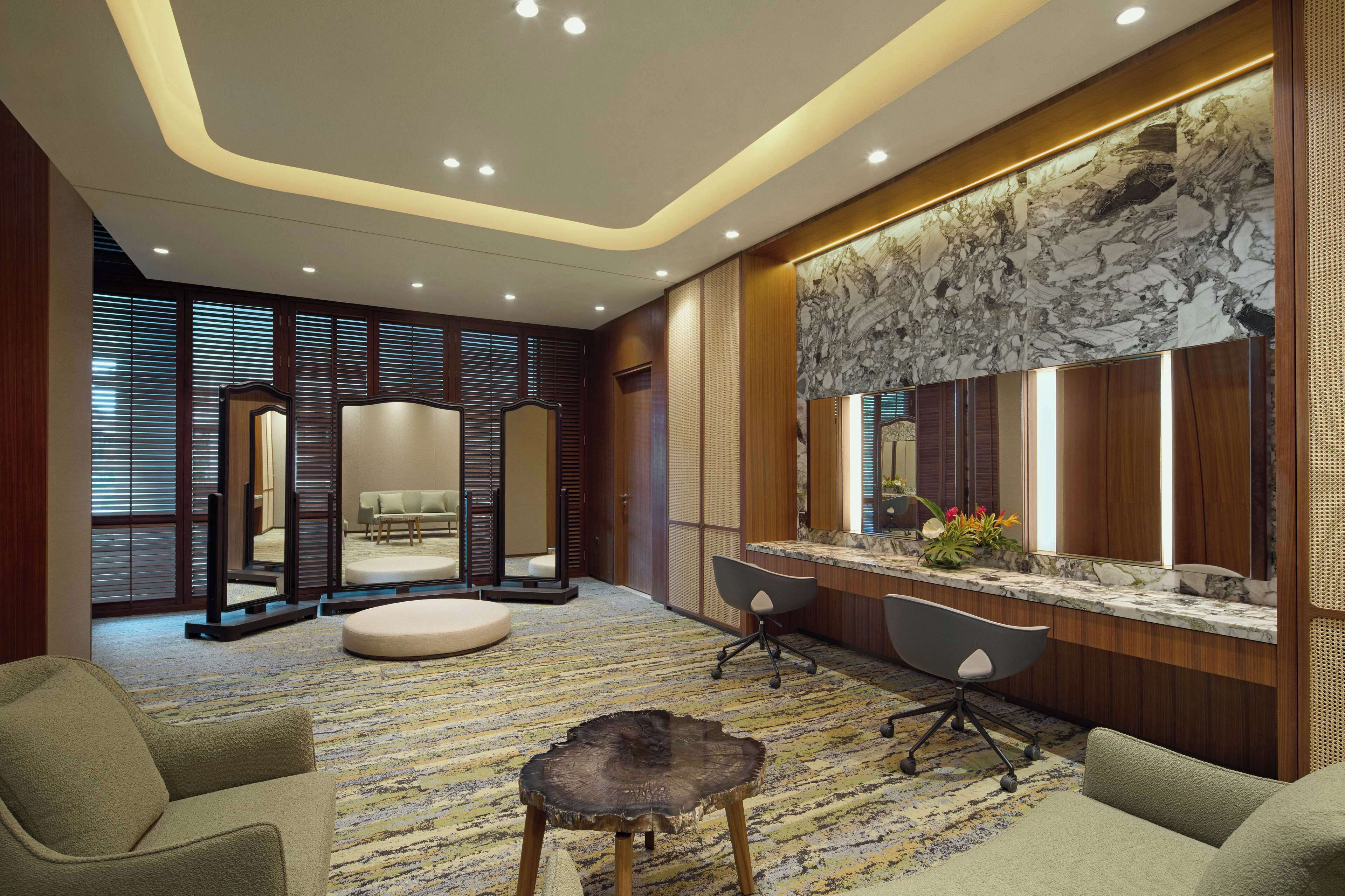 Um interior moderno com área de estar, toucador com espelho e parede decorativa.