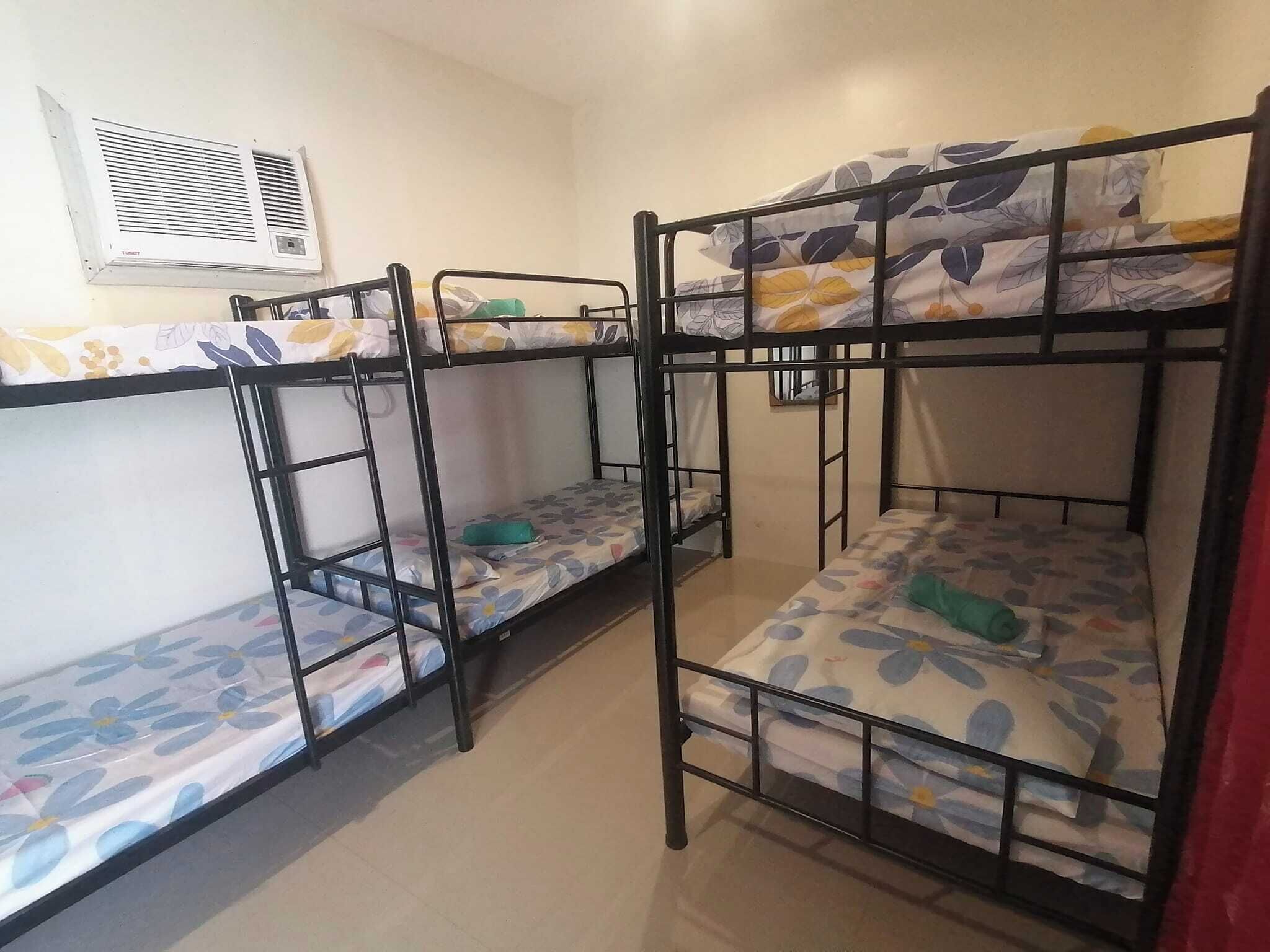 Quarto em dormitório com beliches, janela e ar-condicionado na parede.