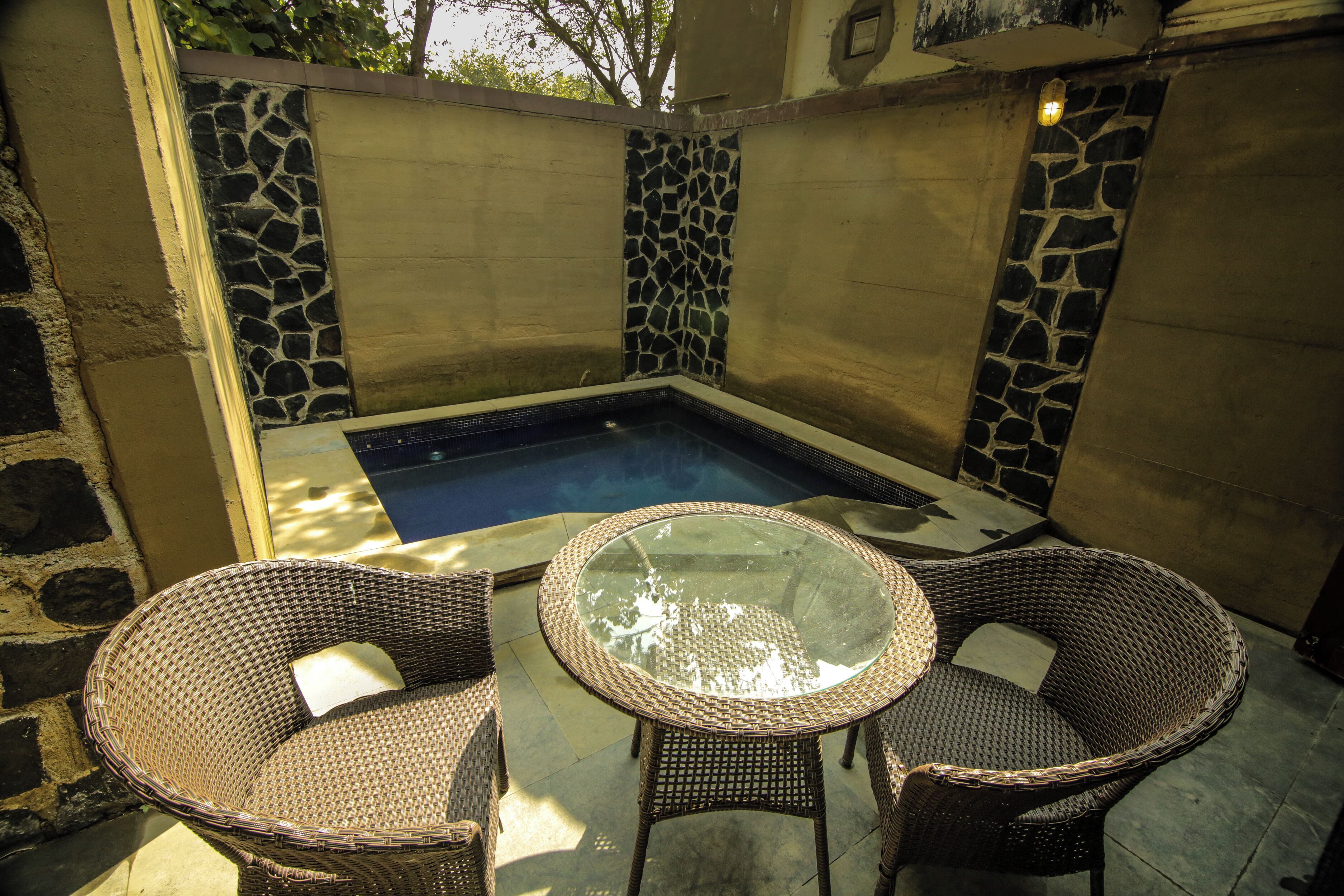 Uma banheira de hidromassagem com mesa de vidro e cadeiras de vime em ambiente externo.
