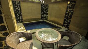 Uma banheira de hidromassagem com mesa de vidro e cadeiras de vime em ambiente externo.
