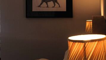 Quarto de hotel com uma cama, uma luminária e um quadro de um leopardo na parede.