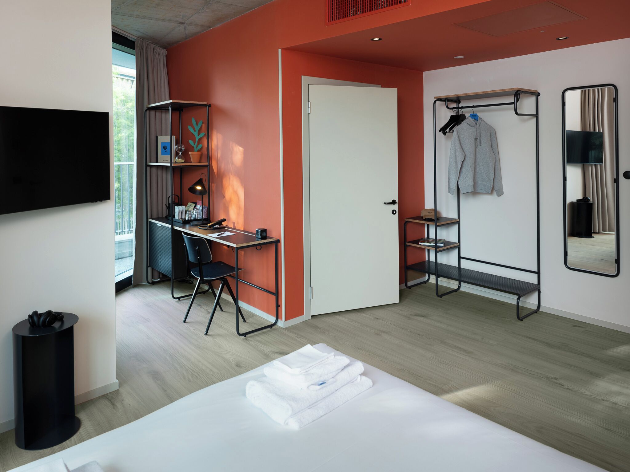 Quarto de hotel moderno com escrivaninha, cadeira e cama com toalhas dobradas com cuidado.