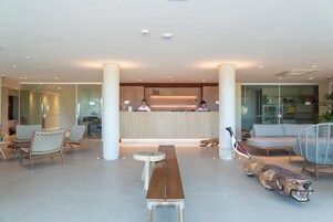 Um hall amplo com balcão de atendimento, área de estar e um grande banco de madeira.