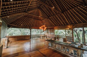 Interior espaçoso em madeira, com teto alto e vista para o verde exuberante lá fora.