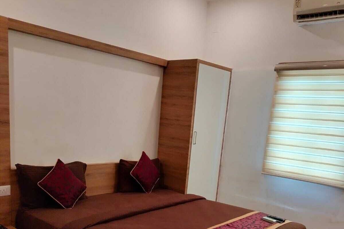 Quarto com estrutura de cama de madeira, mesa de cabeceira, guarda-roupa e janela com persianas.