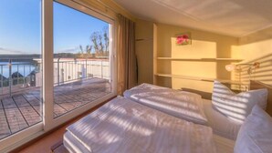 Quarto de hotel com uma varanda ampla, uma cama, uma mesa de cabeceira e uma prateleira na parede.