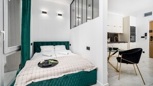 Quarto de hotel moderno com cama grande, área de refeições e cozinha compacta.