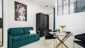 Uma sala de estar moderna com um sofá verde-água, uma mesa de centro de vidro e cadeiras pretas.