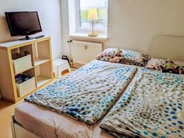 Quarto com cama, televisão, janela e radiador.