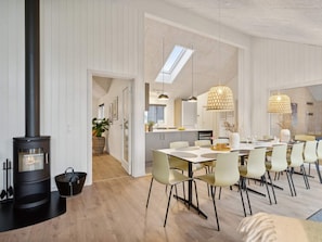 Um interior moderno com área de jantar, cozinha e lareira.