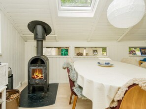 Um quarto acolhedor com lareira a lenha, uma mesa de jantar e uma janela com vista para o verde.