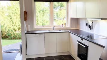 Uma cozinha moderna com armários brancos, bancada preta, janela com vista para o verde e forno embutido.