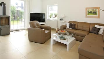 Uma sala de estar com sofá, poltrona e mesa de centro de vidro.