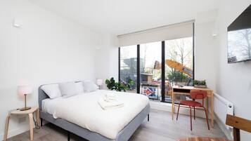 Quarto moderno com cama, mesa de cabeceira, luminária e escrivaninha com cadeira.