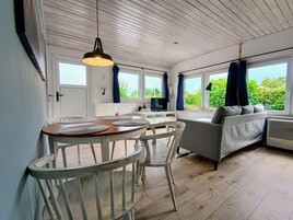 Uma sala de estar moderna com área de jantar, janelas amplas e um ambiente acolhedor.