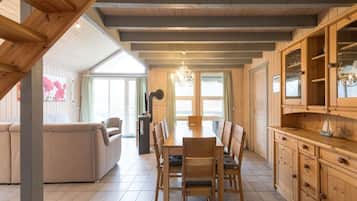 Uma sala de jantar espaçosa com uma mesa e cadeiras de madeira, um sofá e uma área de cozinha com armários de madeira.