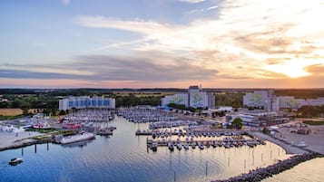 Marina com barcos atracados, cercada por edifícios e um pôr do sol ao fundo.