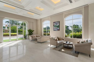 Uma sala de estar espaçosa com grandes janelas, vista para uma fonte e design moderno no teto.