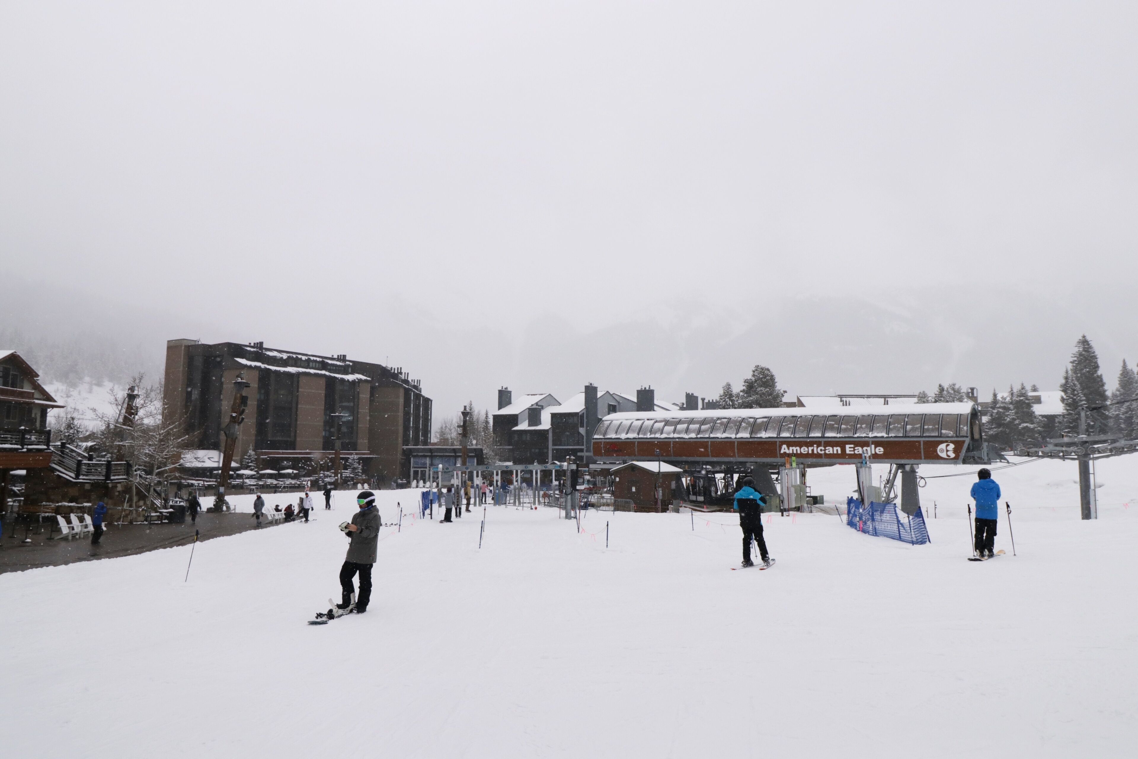 Estância de esqui coberta de neve, com um teleférico e edifícios ao fundo.