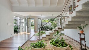 Um interior moderno com soalho de madeira, escada de betão e plantas em vasos.