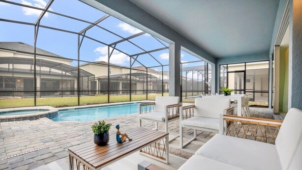 Uma área externa coberta com piscina, assentos e vista para uma casa através de uma estrutura de estufa.