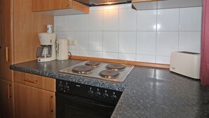 Uma cozinha com armários de madeira, fogão embutido, cafeteira e torradeira.
