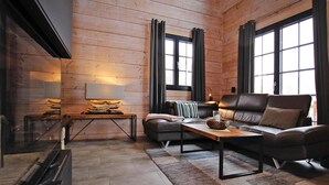 Uma sala de estar acolhedora com lareira, sofá de couro e um espaço de jantar com mesa e cadeiras.