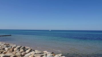 Uma costa rochosa com águas azul-claras e um barco ao longe.