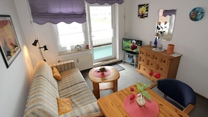 Uma sala de estar acolhedora, com um sofá, uma mesa de madeira e uma televisão.