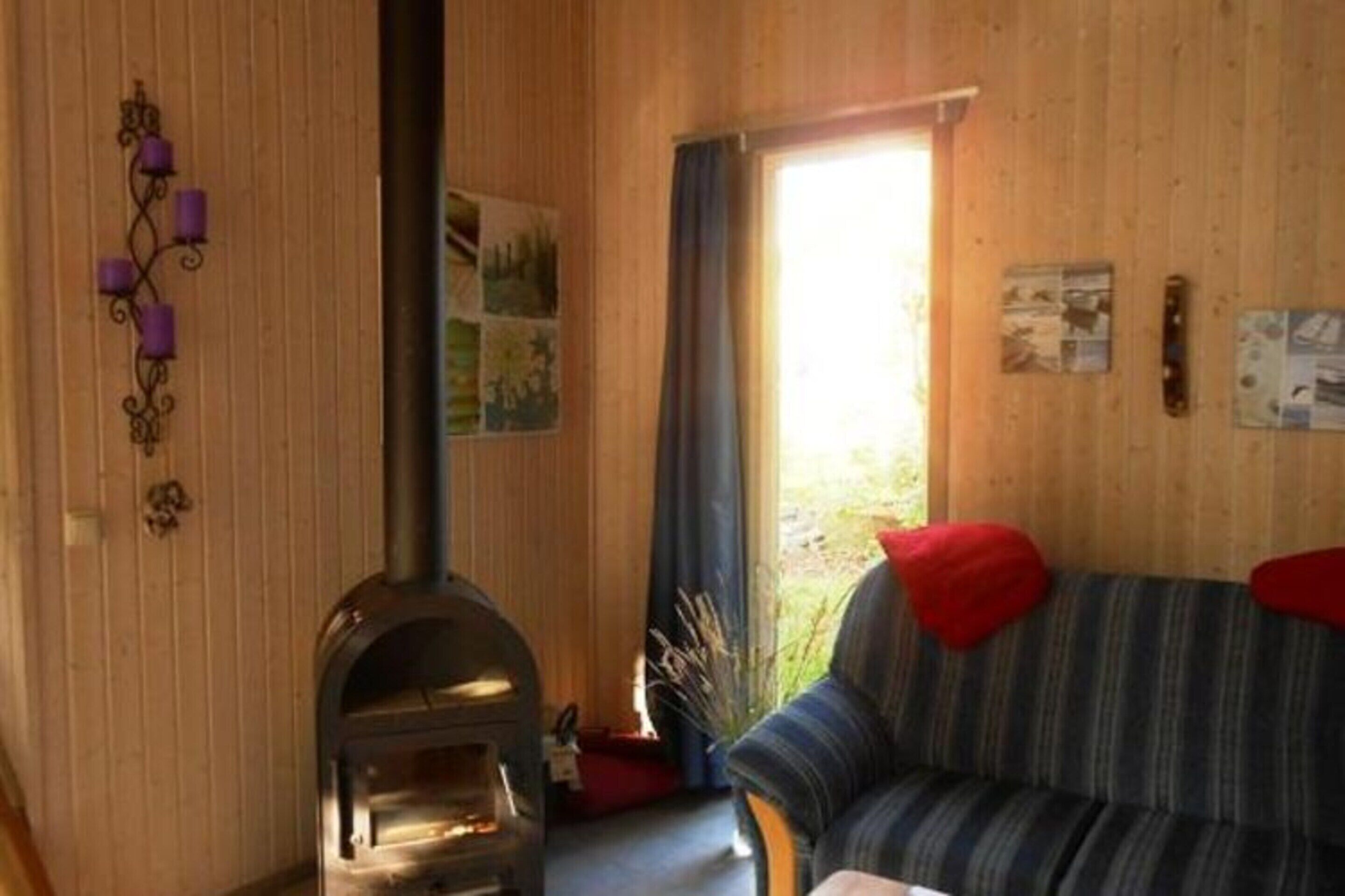 Uma sala de estar aconchegante com lareira, um sofá listrado e uma janela com cortinas.