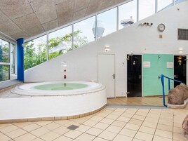 Uma área de hidromassagem com piso ladrilhado, uma porta branca e um corrimão azul.