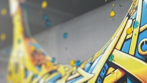 Uma obra de arte abstrata e colorida, com formas geométricas e salpicos de amarelo e azul.