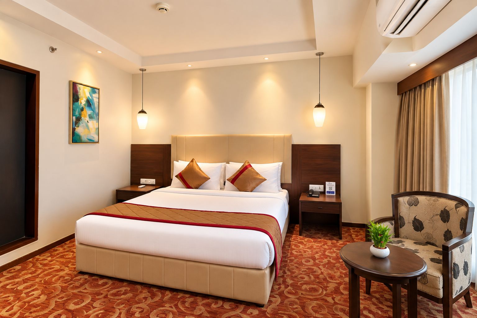 Quarto de hotel com uma cama grande, mesas de cabeceira, uma cadeira, uma pequena mesa com uma planta e um quadro na parede.