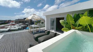 Uma área de piscina no terraço com deck de madeira, uma espreguiçadeira e um grande guarda-sol.