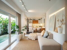 Uma sala de estar moderna com um sofá, uma mesa de centro e uma grande janela com vista para um jardim.