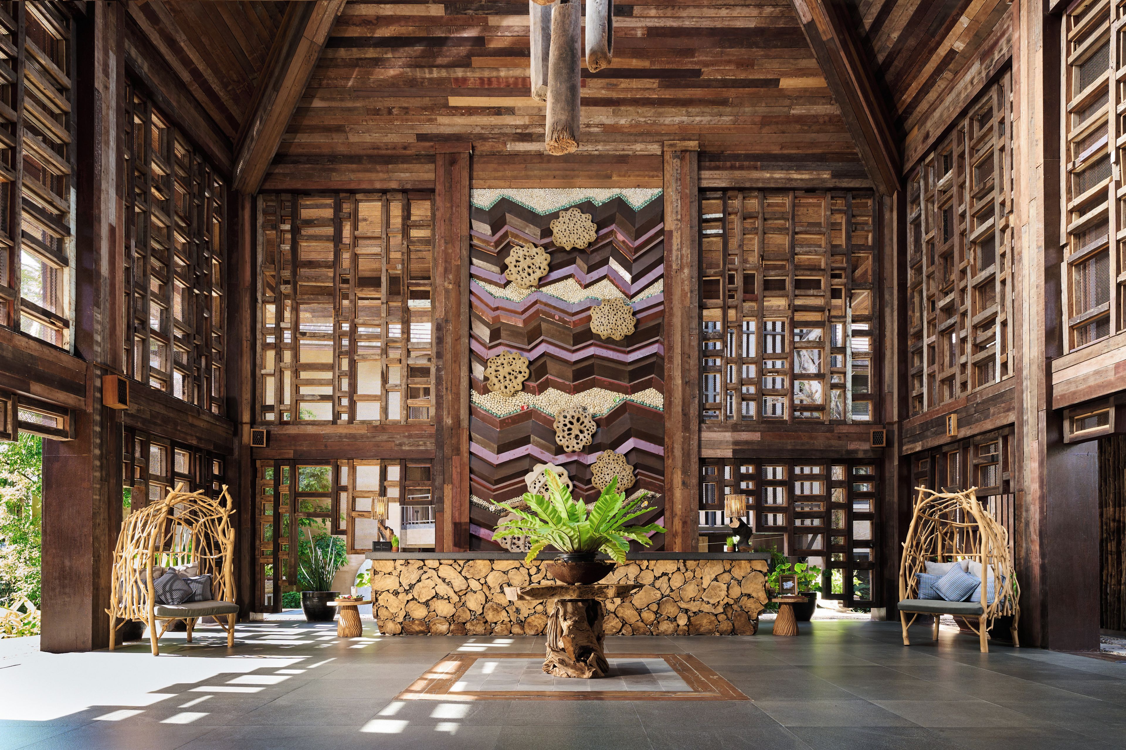 Um hall espaçoso com pé direito alto, vigas de madeira e um grande painel decorativo.