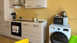 Uma cozinha compacta com pia, fogão, forno e máquina de lavar.