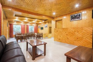 Um interior de madeira com área de jantar, mesas e cadeiras.