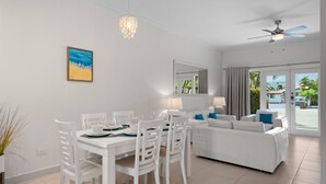 Uma sala de jantar moderna com móveis brancos, um candelabro e um ventilador de teto.