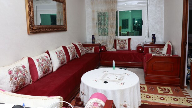 Uma sala de estar com um sofá vermelho, uma mesa de centro redonda e um armário de madeira.