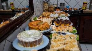 Buffet com diversos alimentos, incluindo pão, doces e sobremesas.