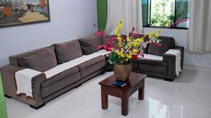 Uma sala de estar com um sofá marrom, uma mesa de centro com um vaso de flores e um quadro na parede.