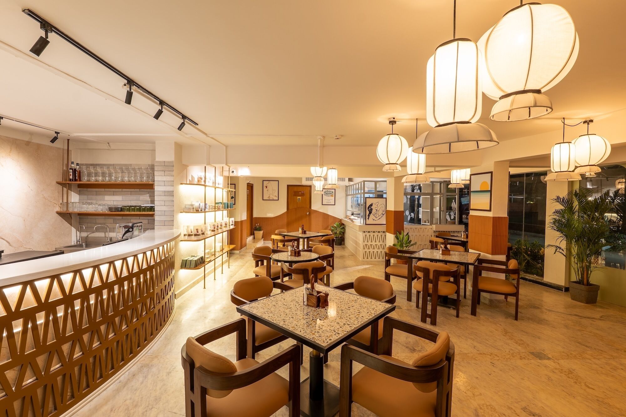 Restaurante com várias mesas e cadeiras, área de bar e iluminação pendente.