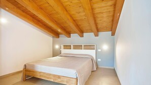 Quarto com teto de madeira, cama com cabeceira e piso claro.