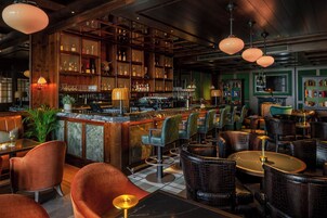 Uma área de bar com assentos, balcão e prateleiras com garrafas.