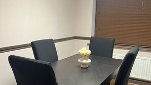 Uma sala de conferência com uma mesa de madeira escura e quatro cadeiras pretas.